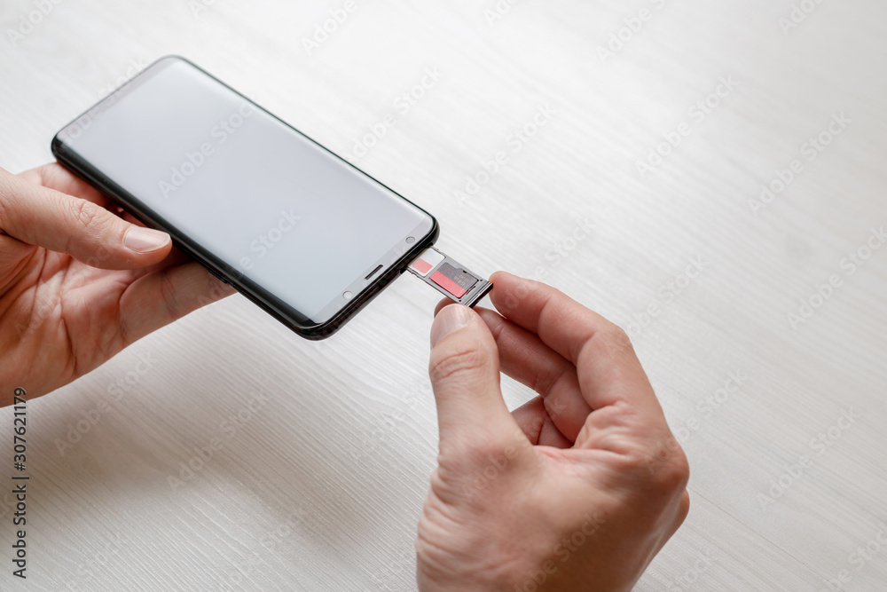 Inserting SIM and mini SD adapter into the phone concept. Hand holding ...