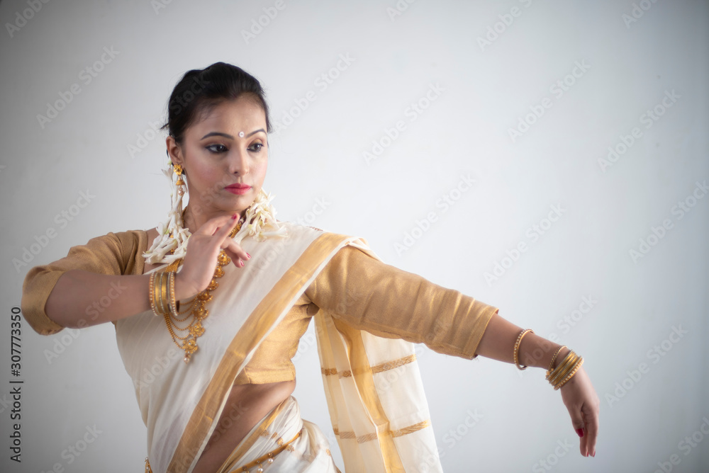 An young and attractive Indian woman in white traditional wear dancing ...