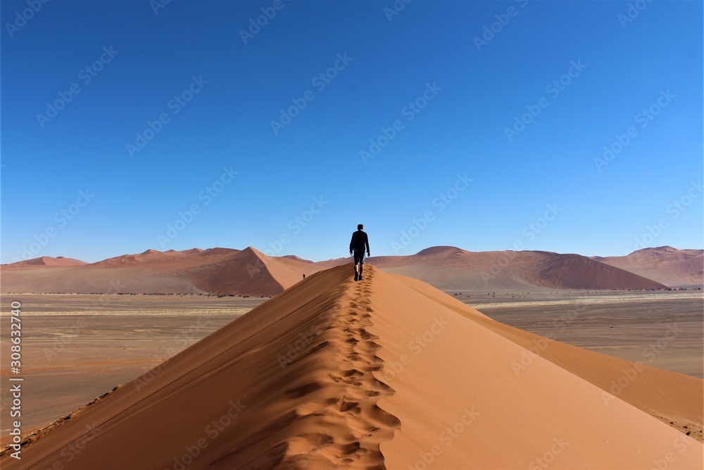 Foto de Stock Man walking on one of the highest dunes in the world ...