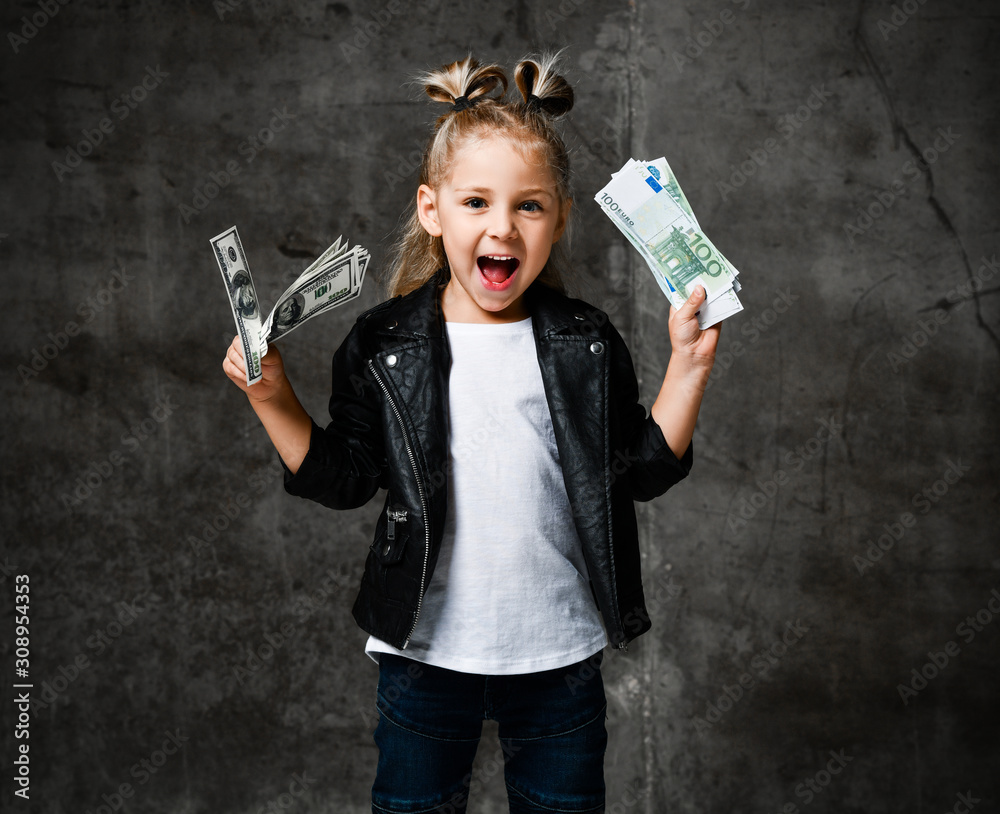 Happy lucky rich kid girl millionaire holds in hands shakes a bundle of ...
