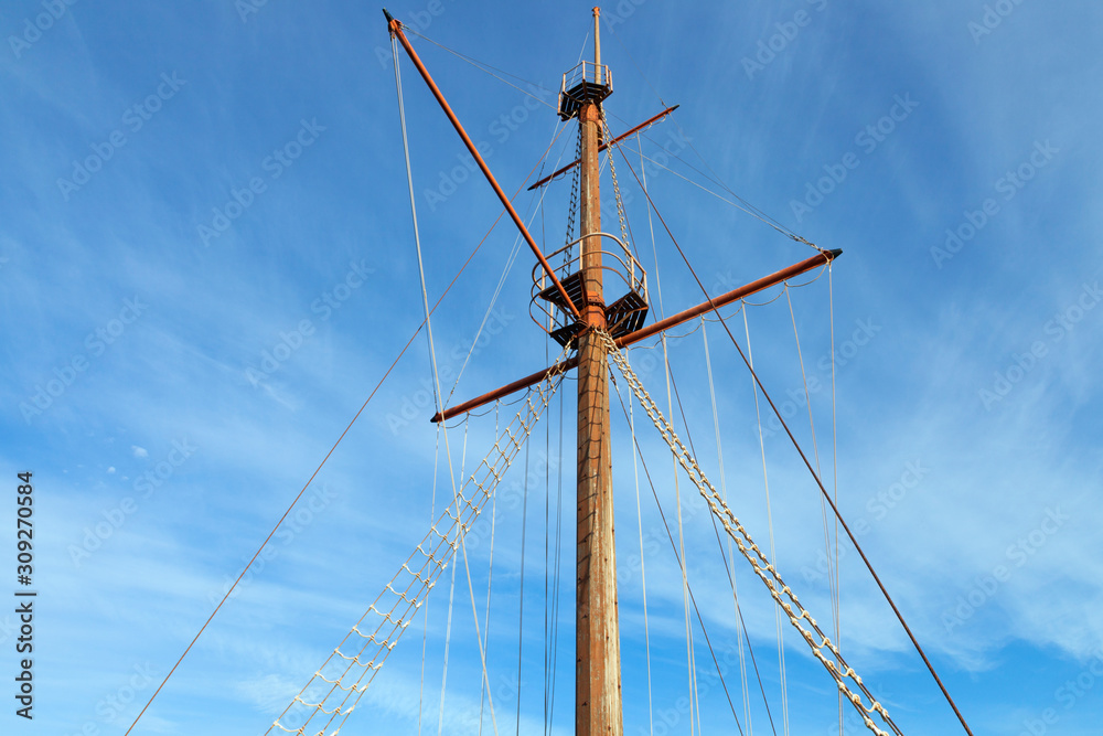 Wooden top of the old sailing ship mast, yards and rigging against blue ...