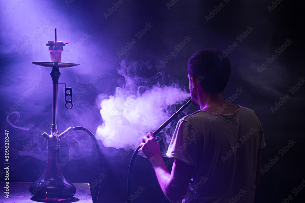 The man Smoking the classic Shisha. Beautiful background, with colored ...