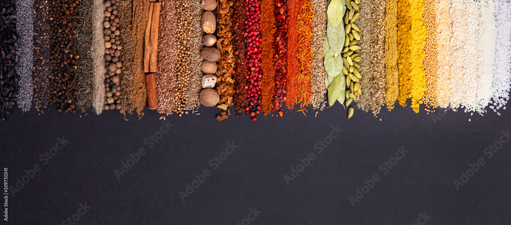 Seasoning, spice and herbs on black background with copy space ...