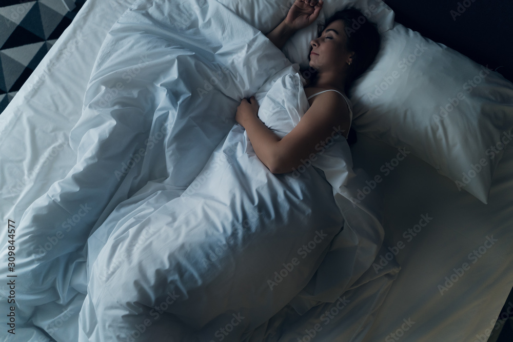 Young beautiful girl or woman sleeping alone in big bed at night, top ...
