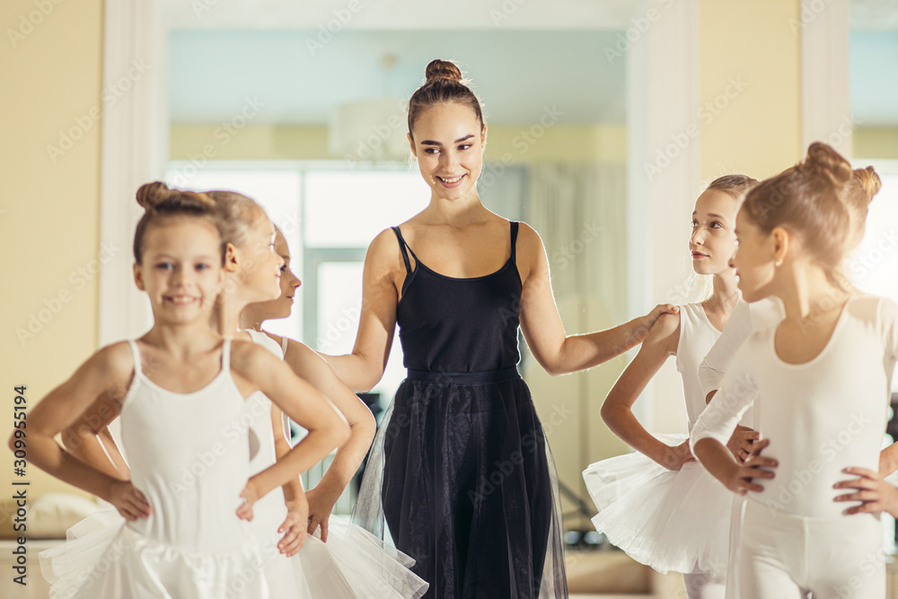young trainer of the ballet school helps young ballerinas perform ...