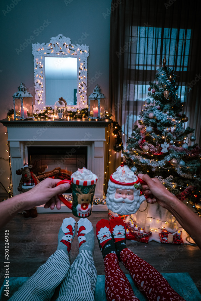 cute couple christmas tree couple drinking hot chocolate under christmas tree by the fireplace in living room Stock Photo Adobe Stock