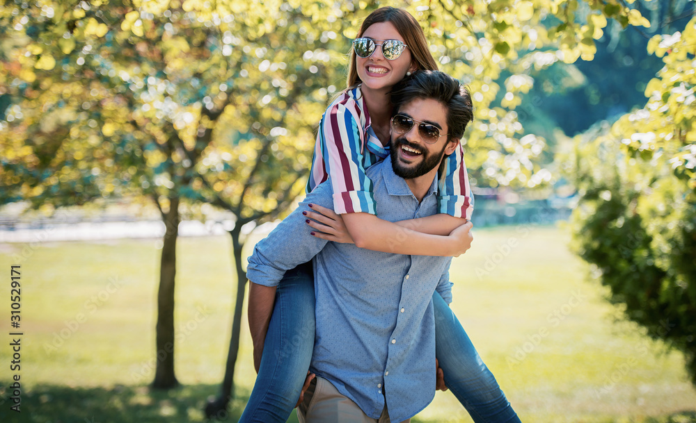 Meeting in the park. Boyfriend carrying his girlfriend on piggyback ...