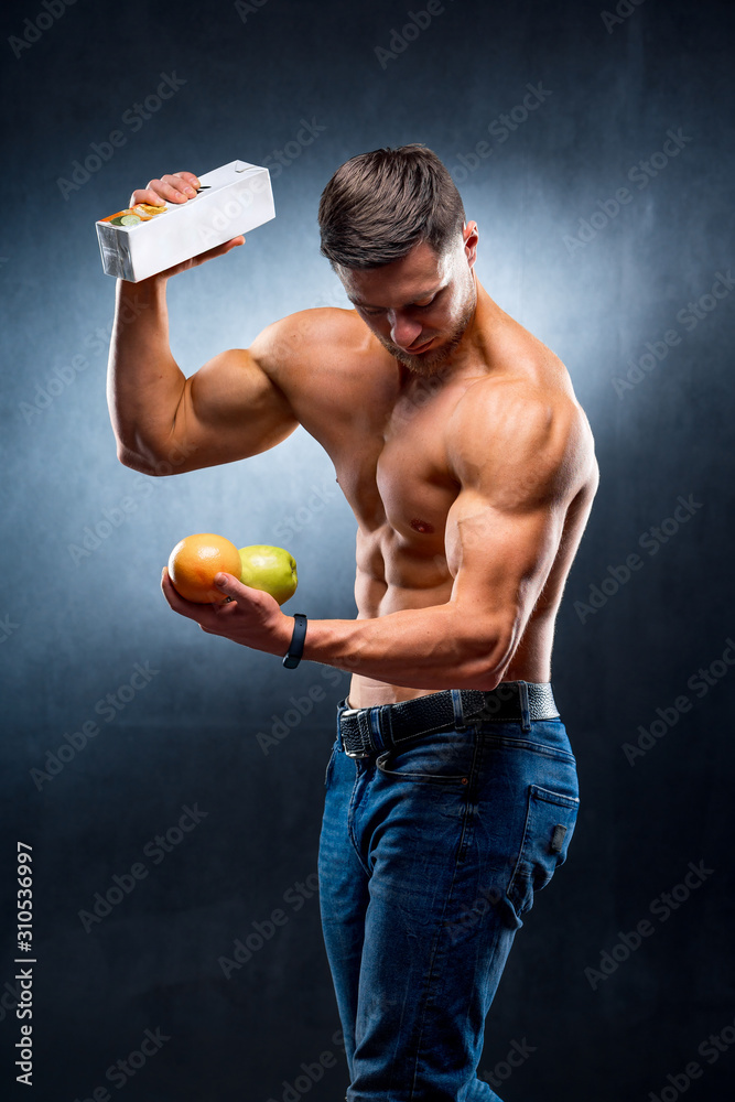 Bodybuilder sportsman holding fruits and juice. Choosing between pure ...