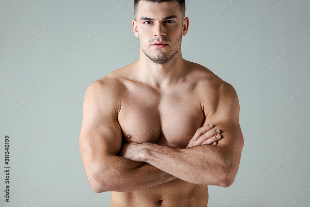 sexy muscular bodybuilder with bare torso posing with crossed arms ...