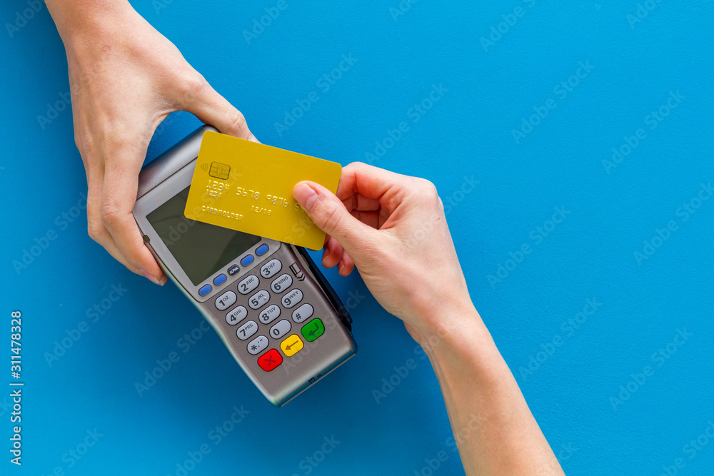 Contactless payment, paypass. Hand hold bank card near terminal on blue ...