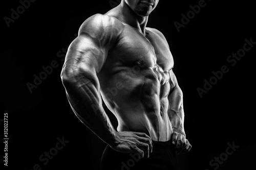 Muscular and fit young bodybuilder fitness male model posing over black ...