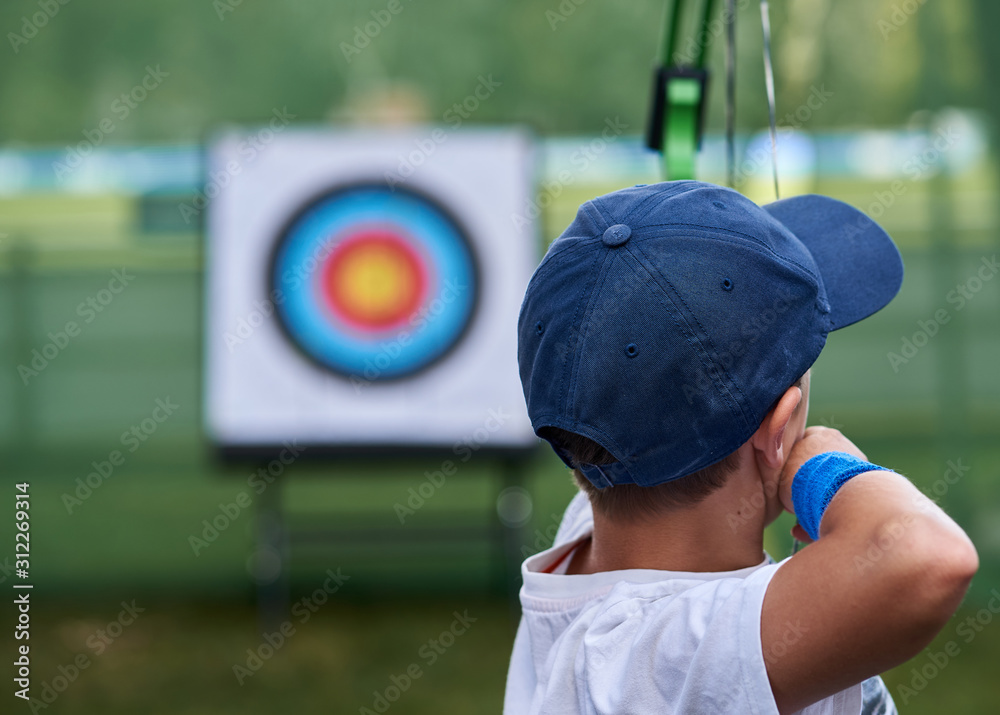 Foto de Stock Young boy aims at a target with his bows and arrows ...