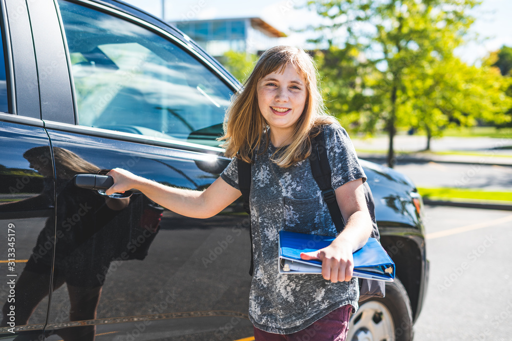 Photo Stock Happy teenage girl standing beside a car/suv getting ...