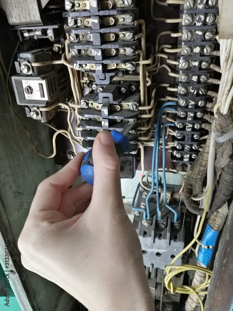 hand with a tool checks the attached electrical wires on the shield on ...