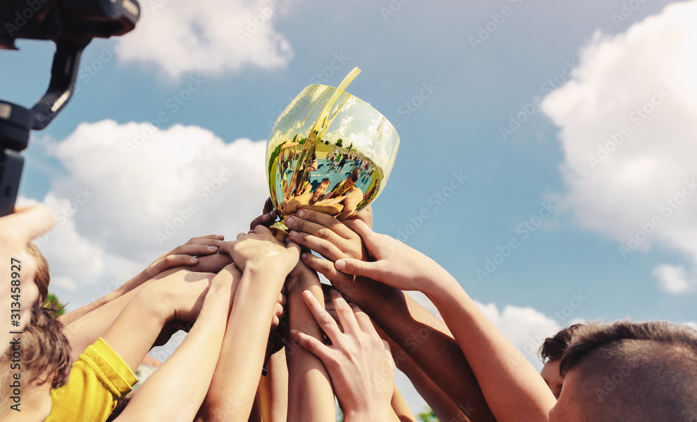 Kids in sports team lift up the golden cup trophy after winning the ...