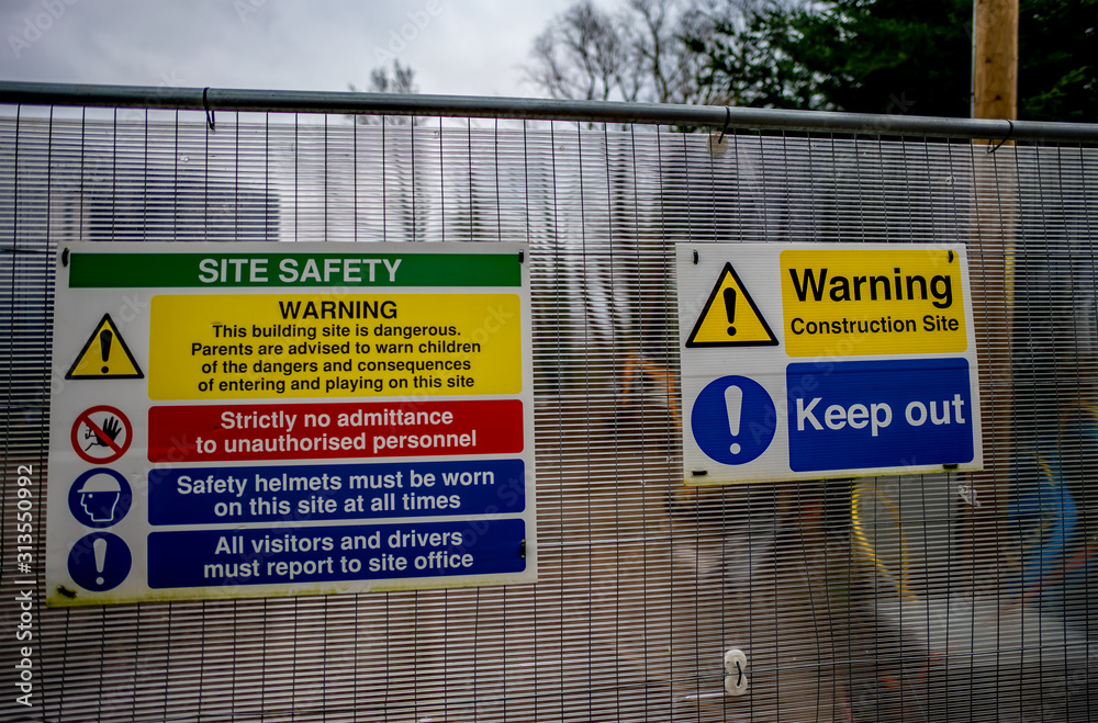 Building site entrance. Wire gate with warnings and permission signs ...