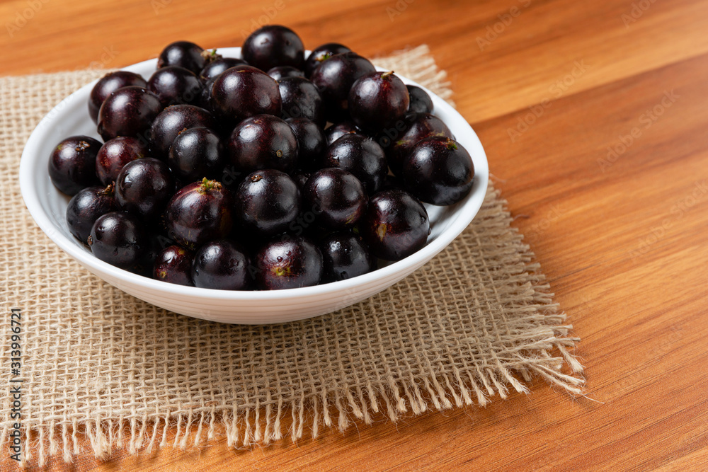 Jabuticaba in the bowl on wooden table. Jaboticaba or Jabuticaba is the ...