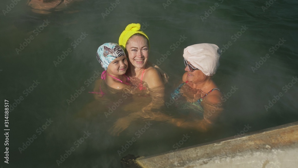 Baby girl, mom and grandmother in a swim in hot saline mineral water bath at a traditional spa ...