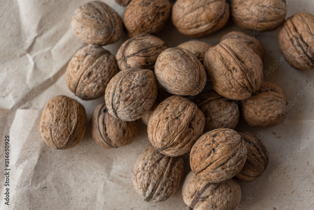 A handful of inshell walnuts on old crumpled kraft paper, brown ...