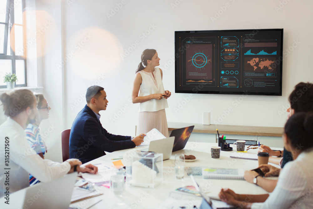 Businesswoman at television screen leading conference room meeting ...