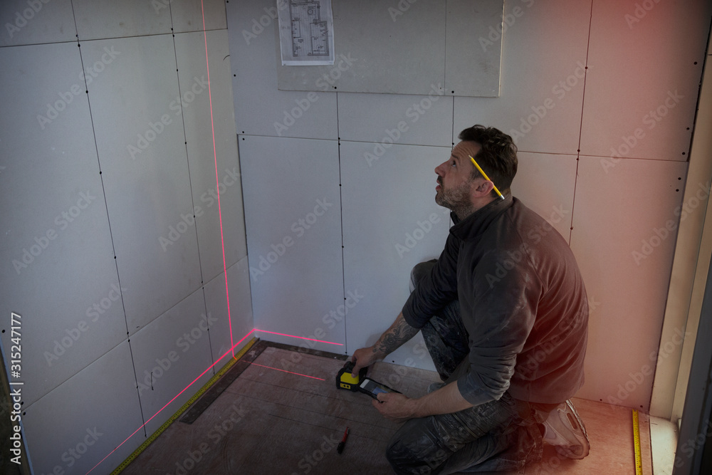 Construction worker using laser measuring tool Stock Photo | Adobe Stock