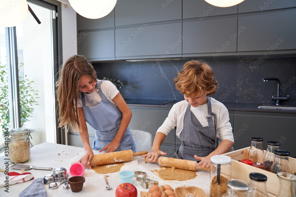From above of male and female little kids in aprons smiling while ...
