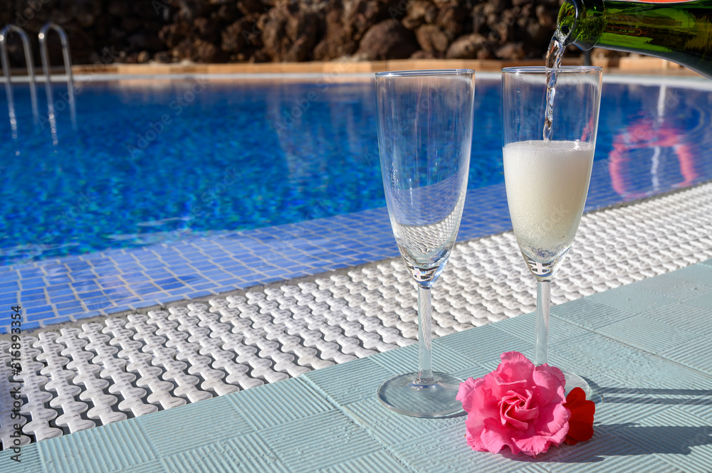 Pool party with two glasses with bubbles white champagne or cava wine ...