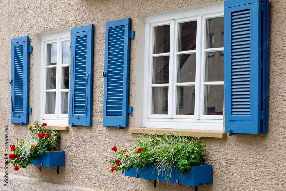 Two windows with white wooden frames blue shutters and decorative flower boxes. Image of trendy decor comfort beautification. Stock Photo Adobe Stock