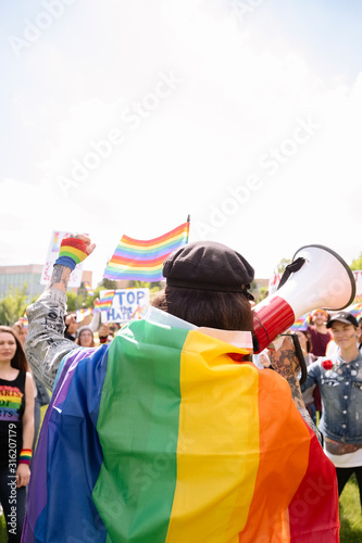 Gay pride activist wearing rainbow flag and using megaphone Stock Photo ...