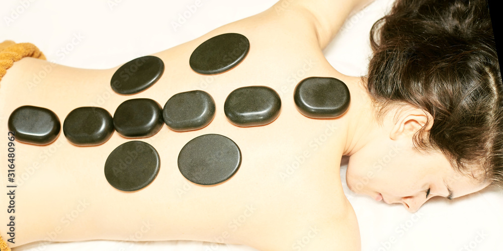 body stone massage. Hot rock masseur. Girl at salon with doctor hands ...