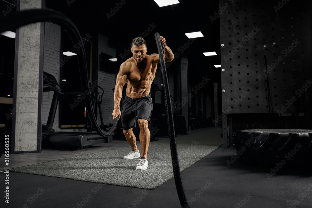 Muscular sportsman training with ropes. Stock Photo | Adobe Stock