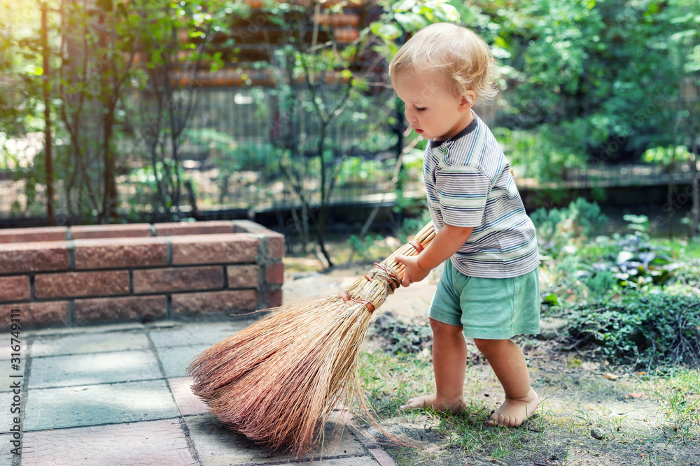 Cute adorable caucasian toddler boy playing holding broom at backyard ...