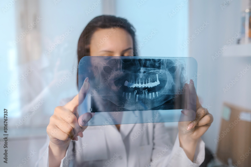 Close up picture of young woman doctor dentist who analysis dental x ...
