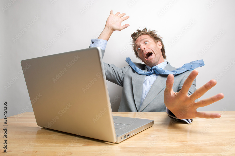 Shocked businessman falling back at his office desk looking at his ...