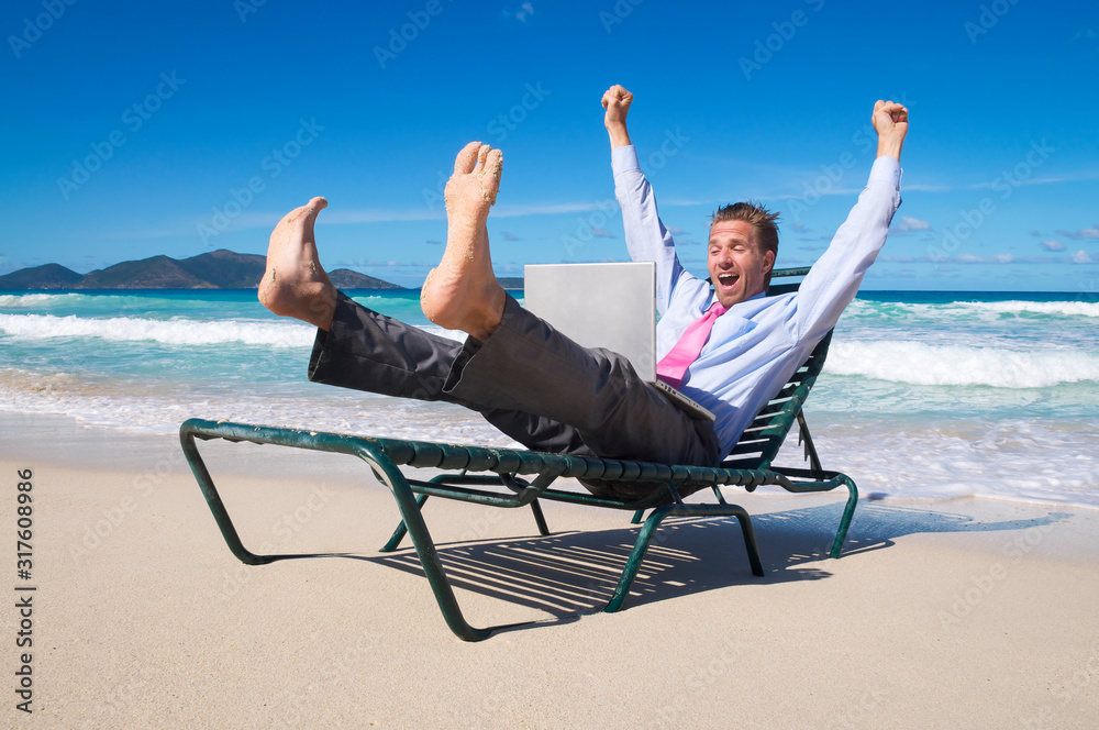 Excited businessman kicking up his bare feet and throwing out his hands ...