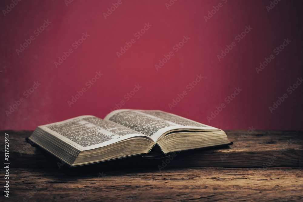 Open bible on a old oak wooden table. Beautiful green wall background ...