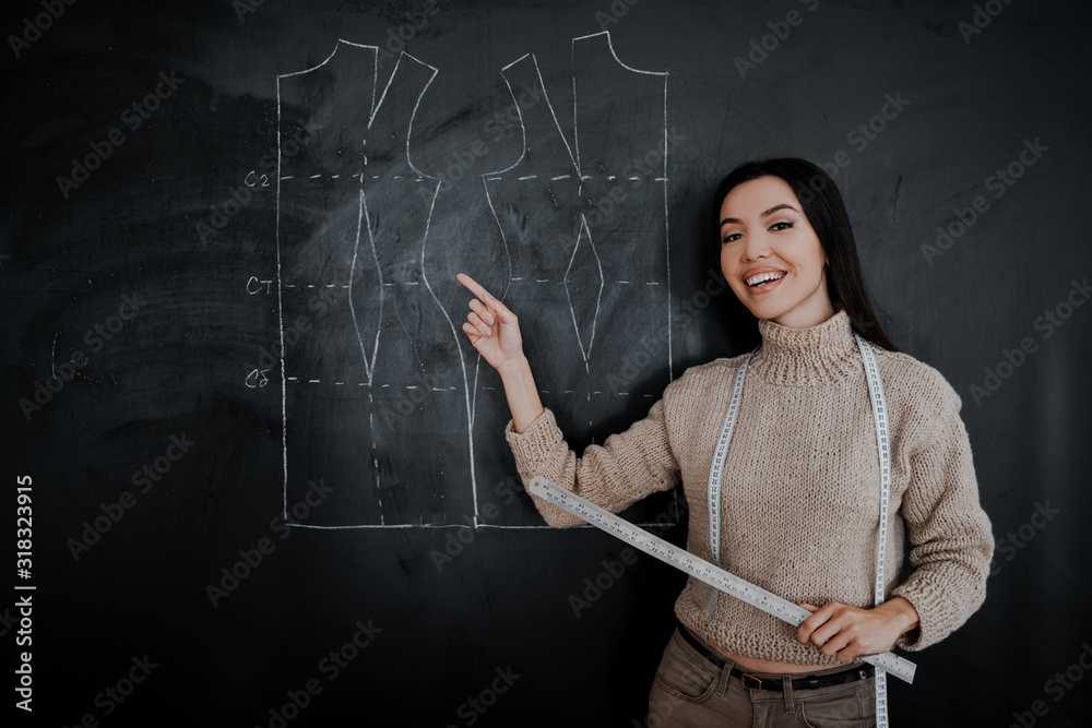 Young Asian woman seamstress points a finger at the drawing on the ...