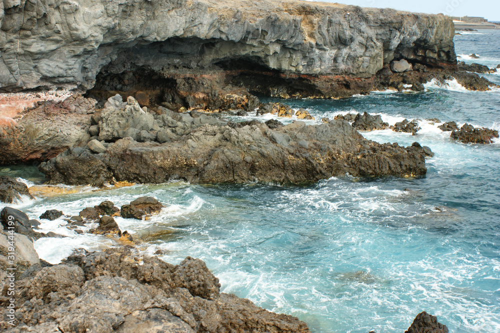 East coast of Tenerife. Rocky grotto and azure sea. Waves constantly ...