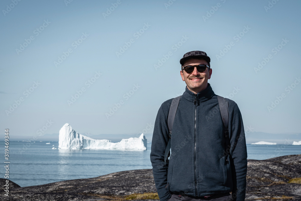 Young man tourist standing in front of iceberg. View towards Icefjord ...