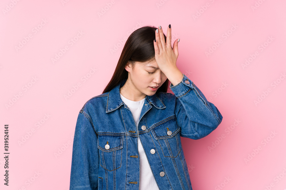 Young chinese woman posing in a pink background isolated forgetting ...