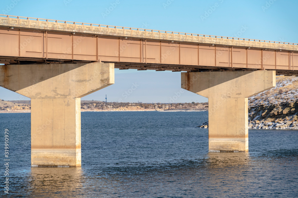 Focus on a beam bridge supported by abutments over blue lake against ...