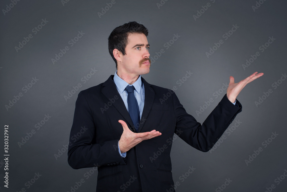 handsome caucasian young businessman pointing aside with both hands ...