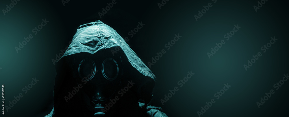 man in the gas mask in the hood, on the dark background, survival ...