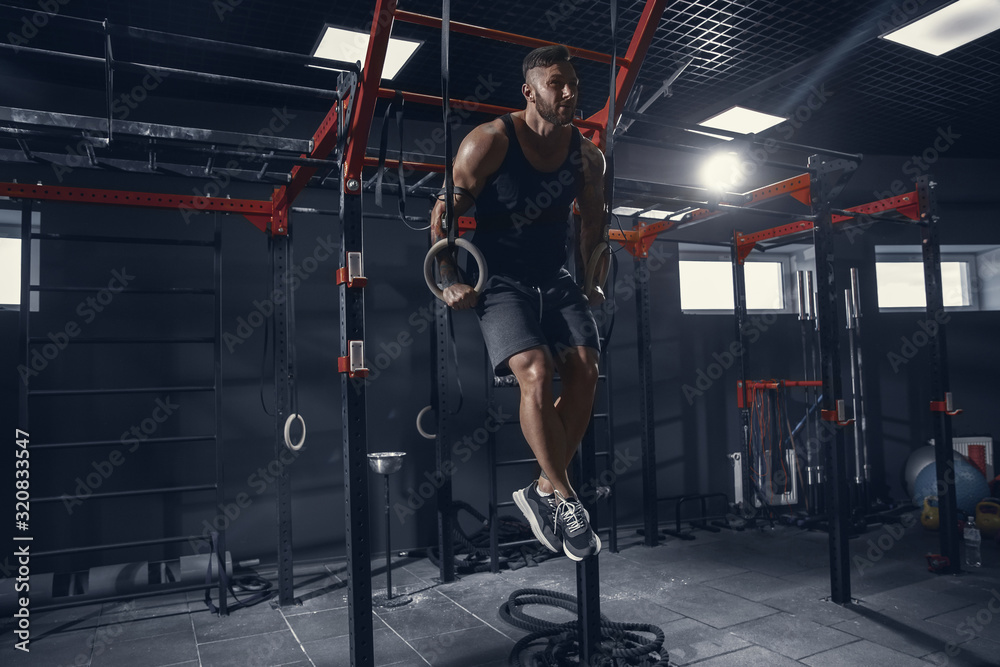 Flying hard. Young muscular caucasian athlete practicing pull-ups in ...