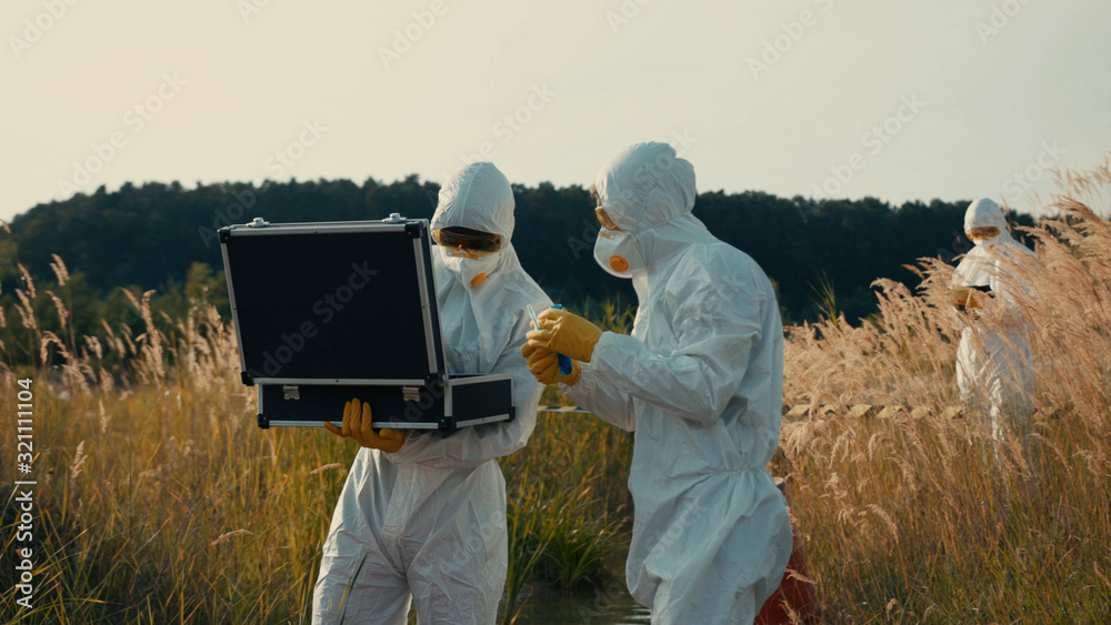 Two ecology experts eamining polluted water sample in test tube working ...
