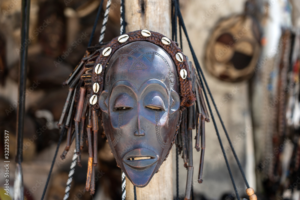 Traditional african wooden masks hanging for sell on the street market ...