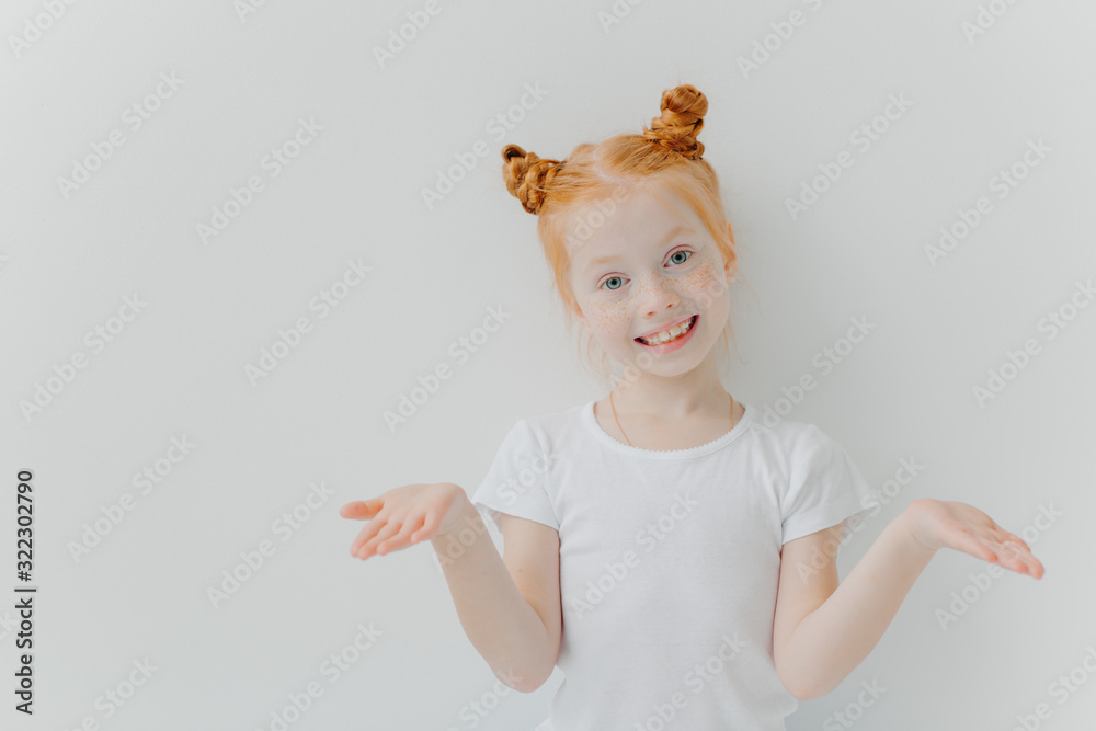 Pretty small female kid with double foxy buns spreads palms sideways ...