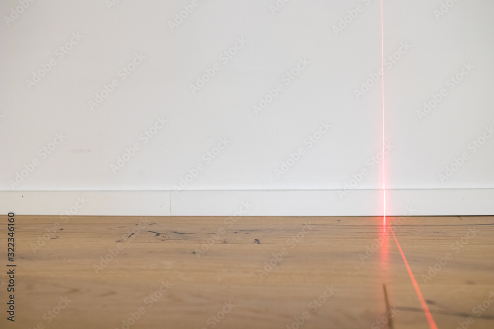 Laser meter on white wall and parquet in new apartment. Precision ...