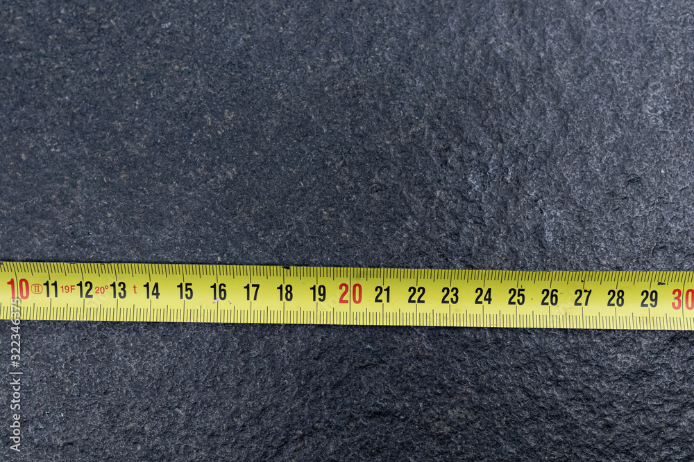 yellow tape measure on black stone. Measurement tools for construction ...