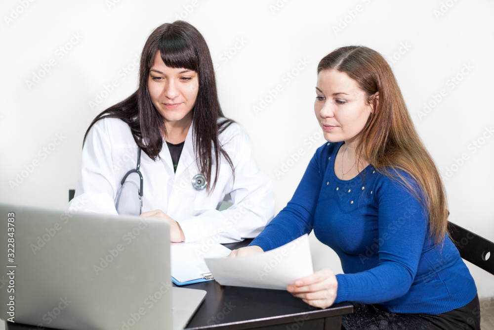Doctor and patient discuss test results at the desk, looking at screen ...